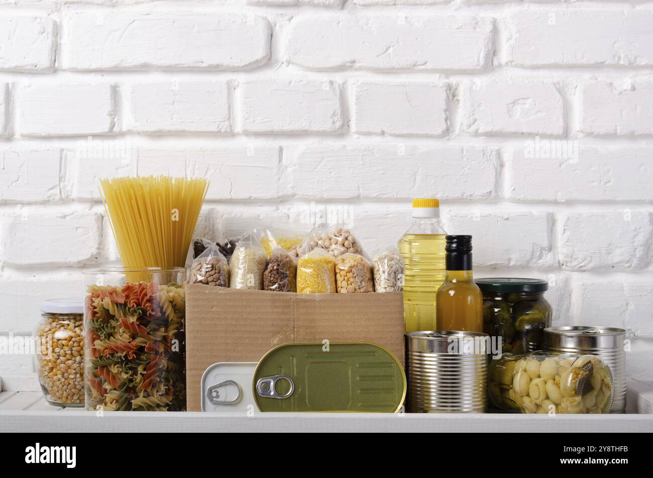 Set of uncooked foods on pantry shelf prepared for disaster emergency ...