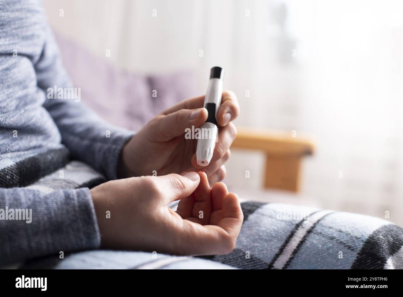Middle age caucasian man sitting on the sofa pierced his finger with ...
