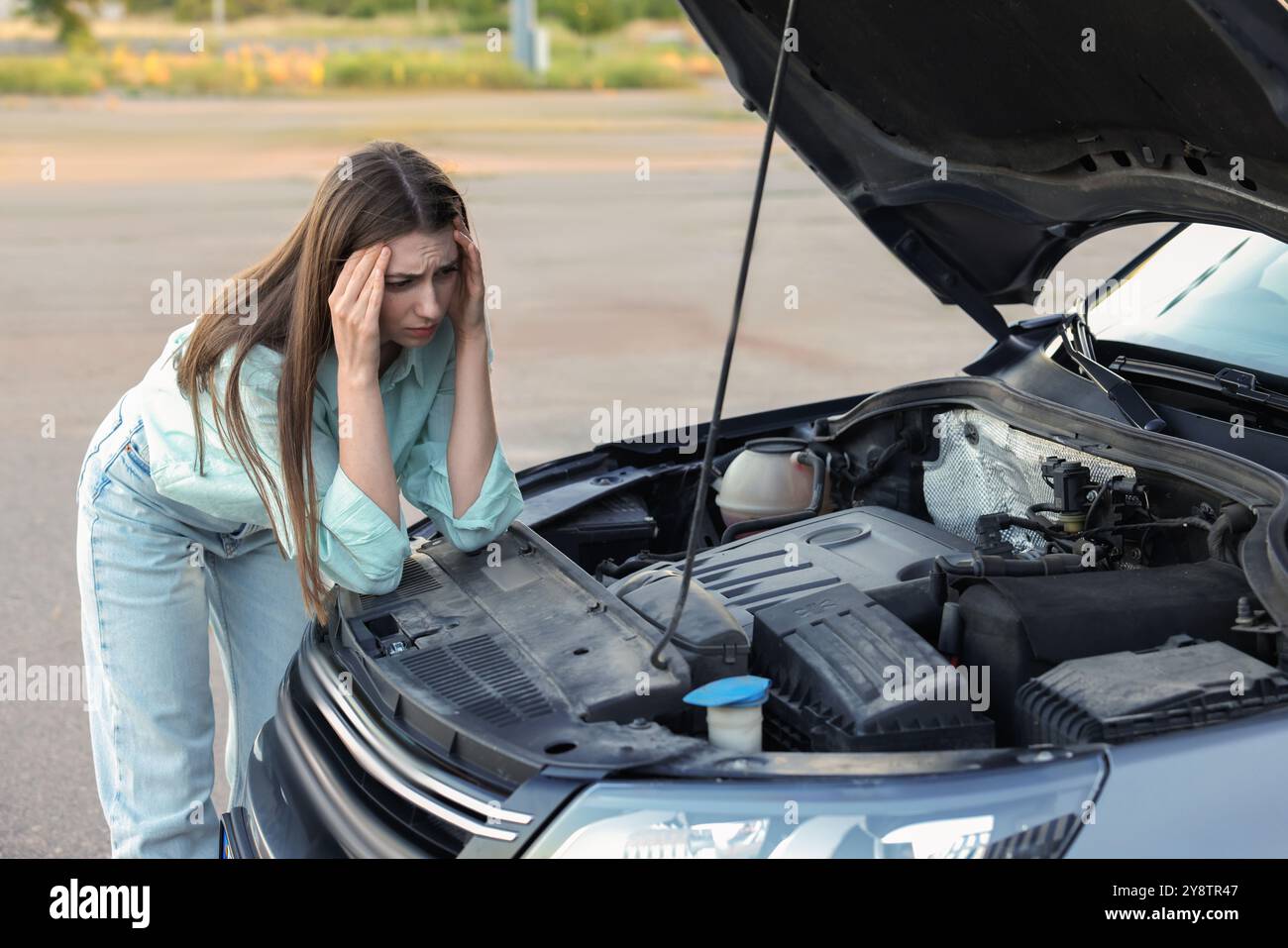 Stressed woman looking under hood of broken car outdoors Stock Photo - Alamy