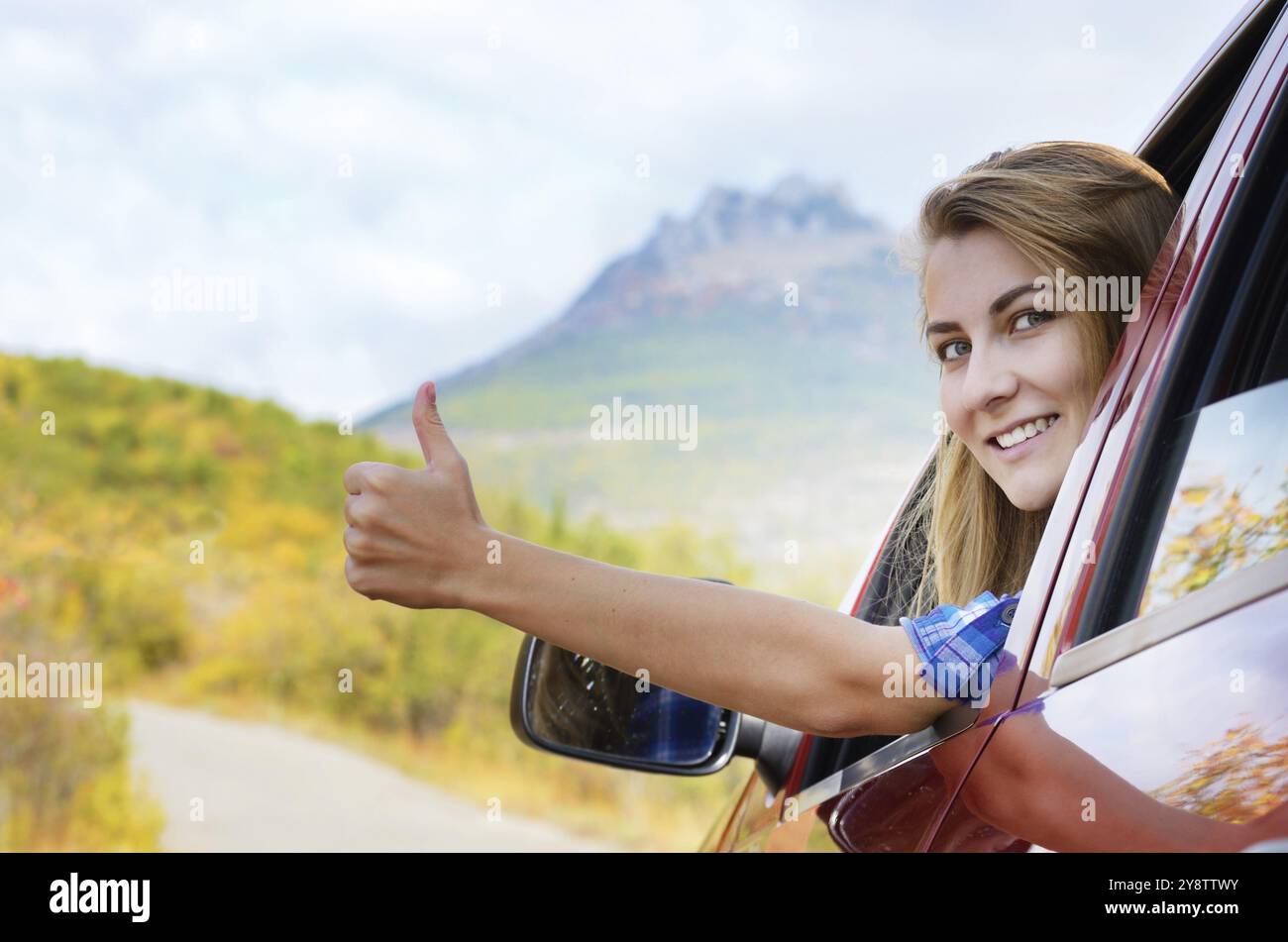 Happy driver woman shows thumb up against mountains background. Travel ...