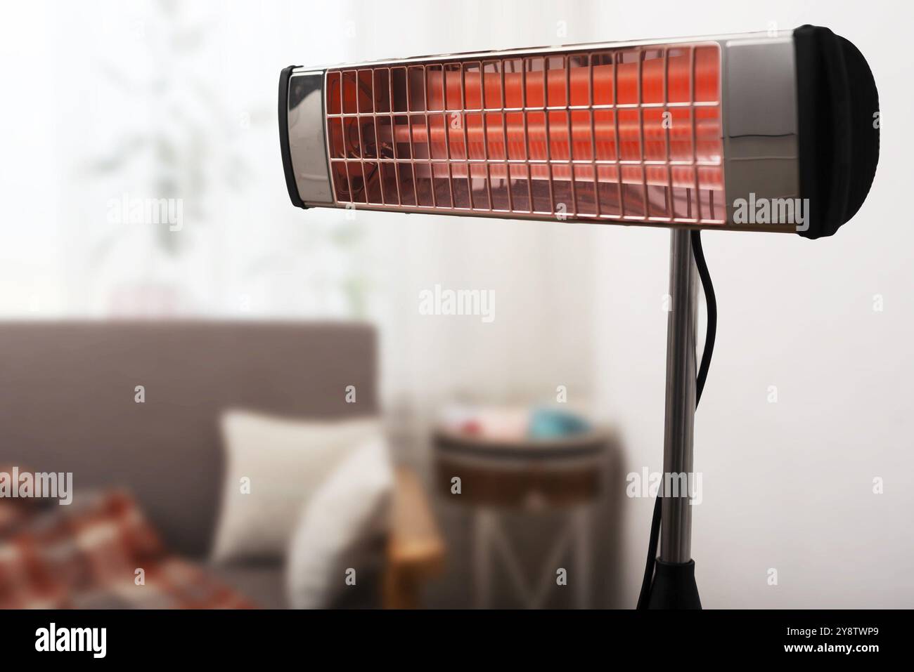 Electric infrared heater warming up living room with sofa and potted ...