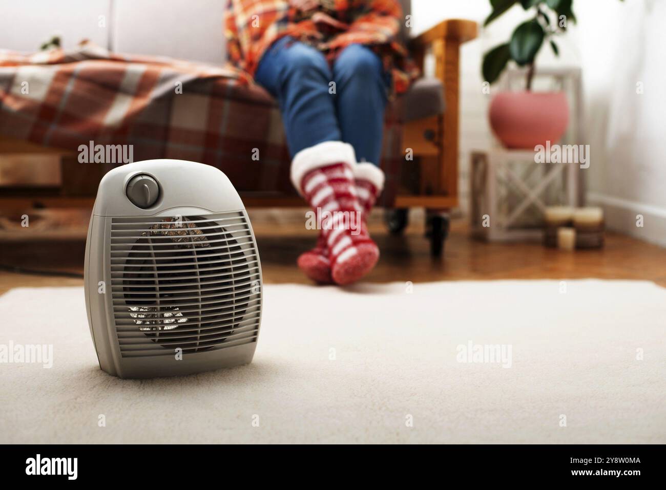 Electric fan heater on the floor in living room with human sitting on ...