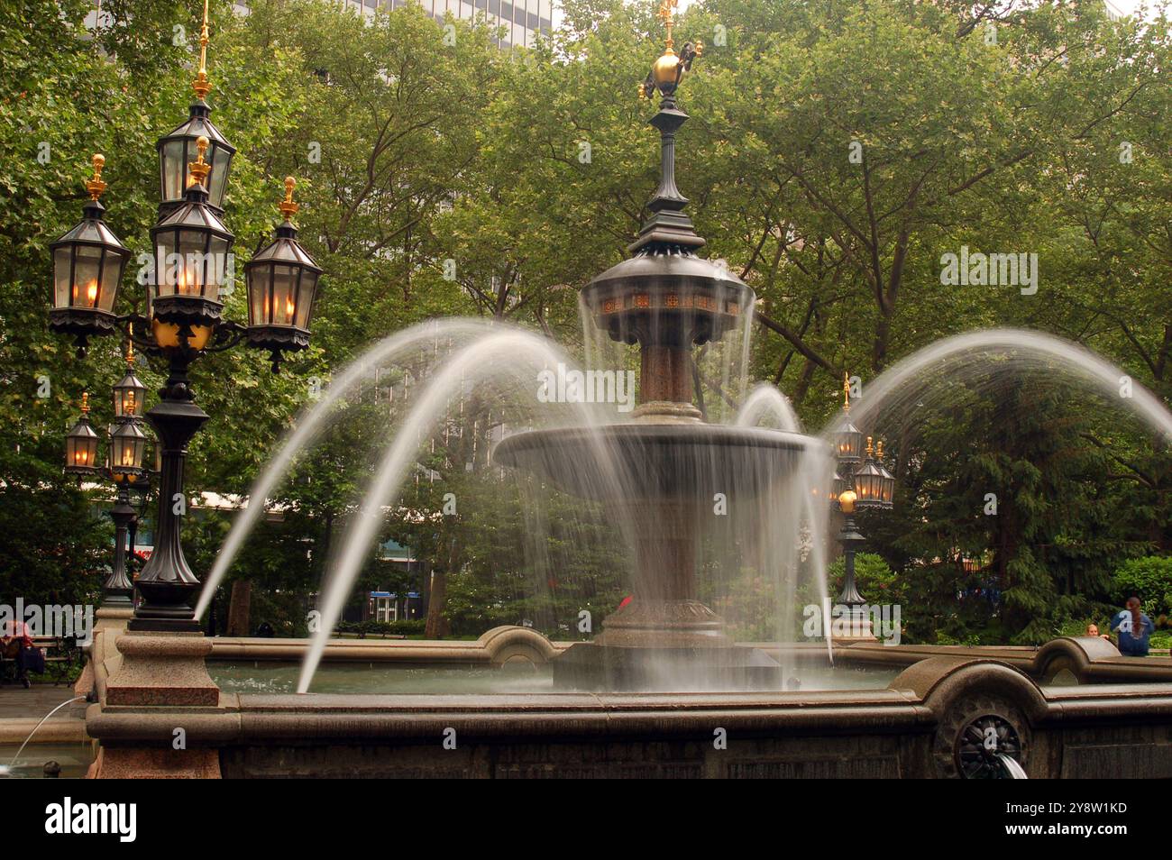 A water fountain front of the New York City Hall flows in a lush park ...