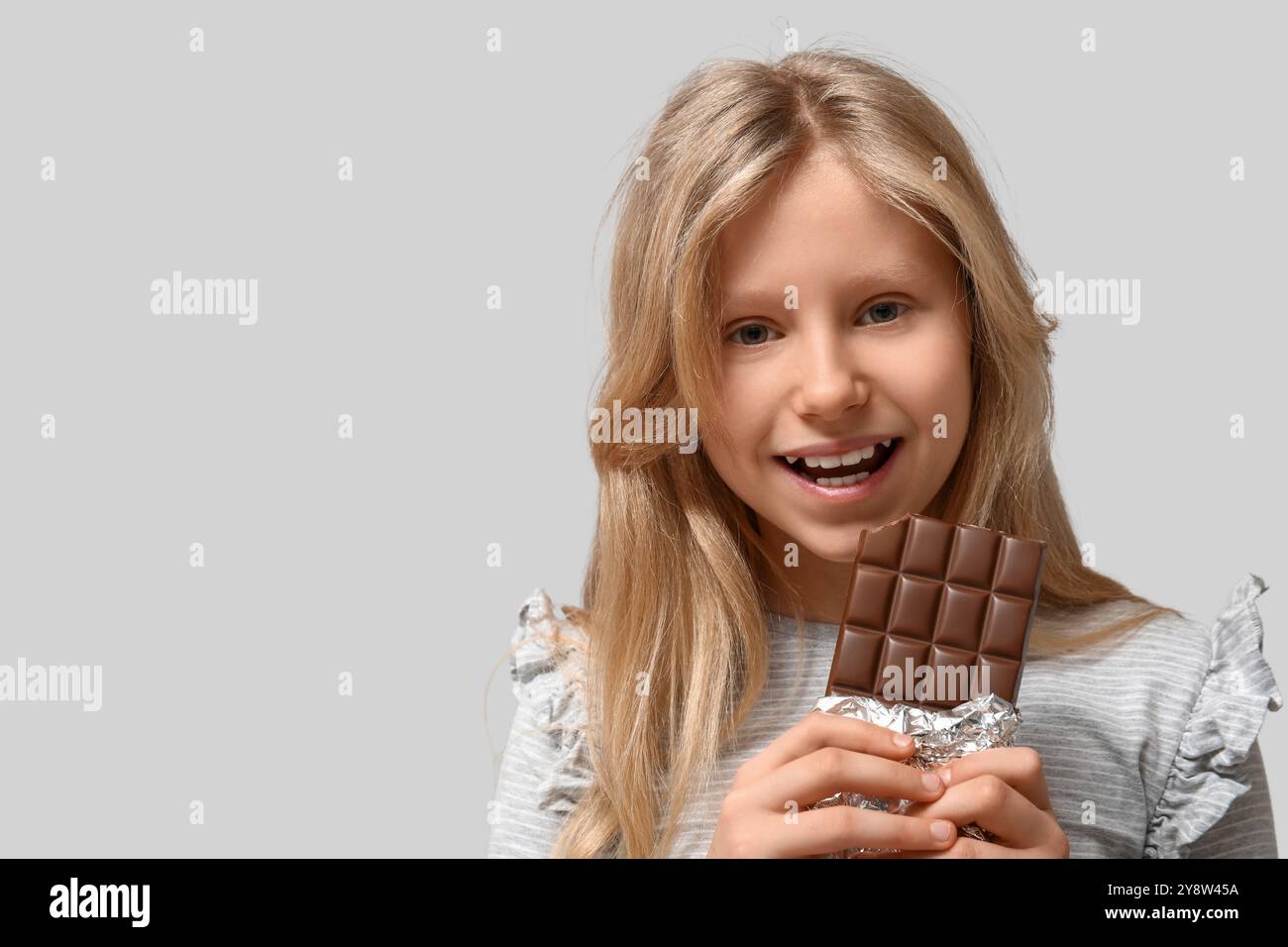 Cute little girl with sweet chocolate bar on grey background Stock ...