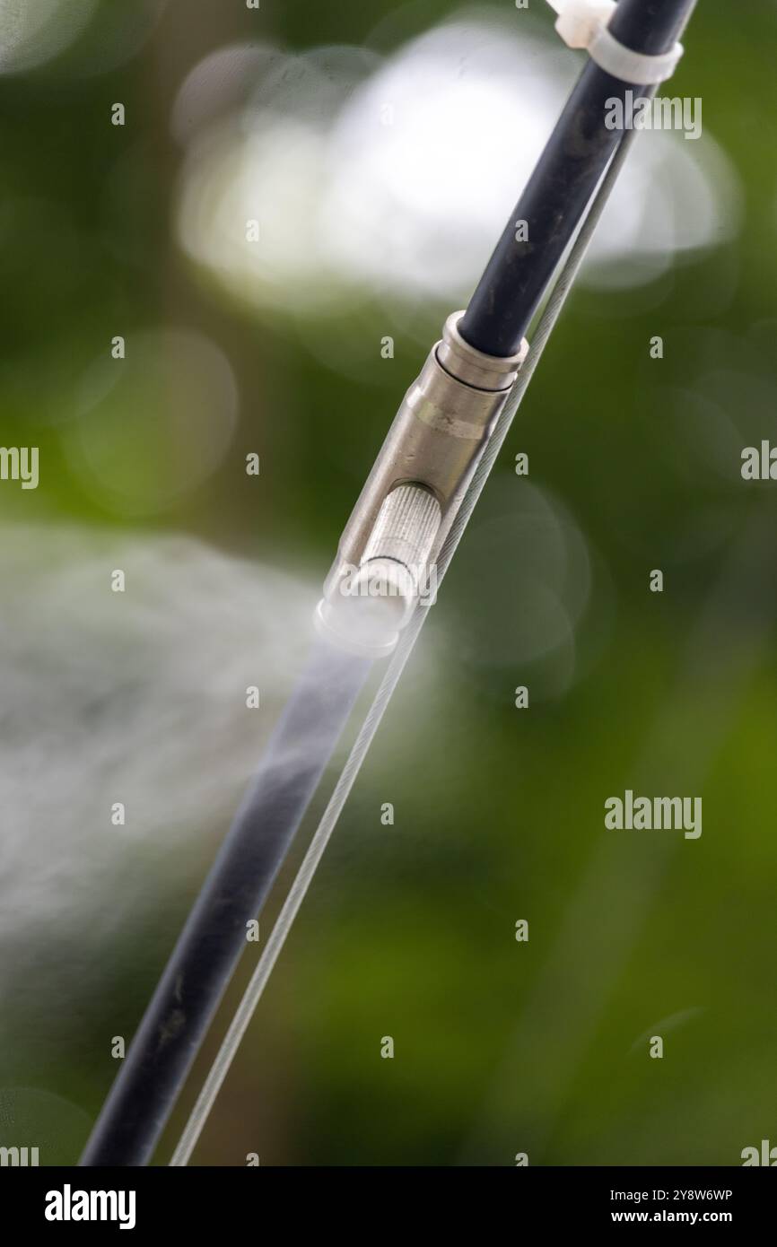 Water aerosol is jetting from a hanging hose in the garden, close up ...