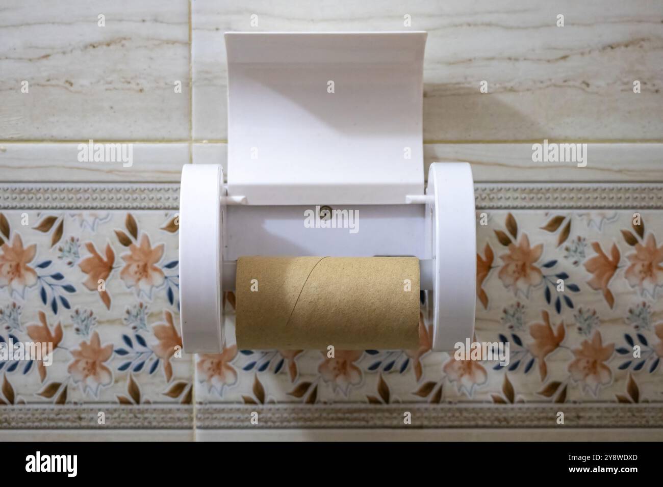 Toilet tissue paper holder with an empty cardboard cylinder on ceramic ...