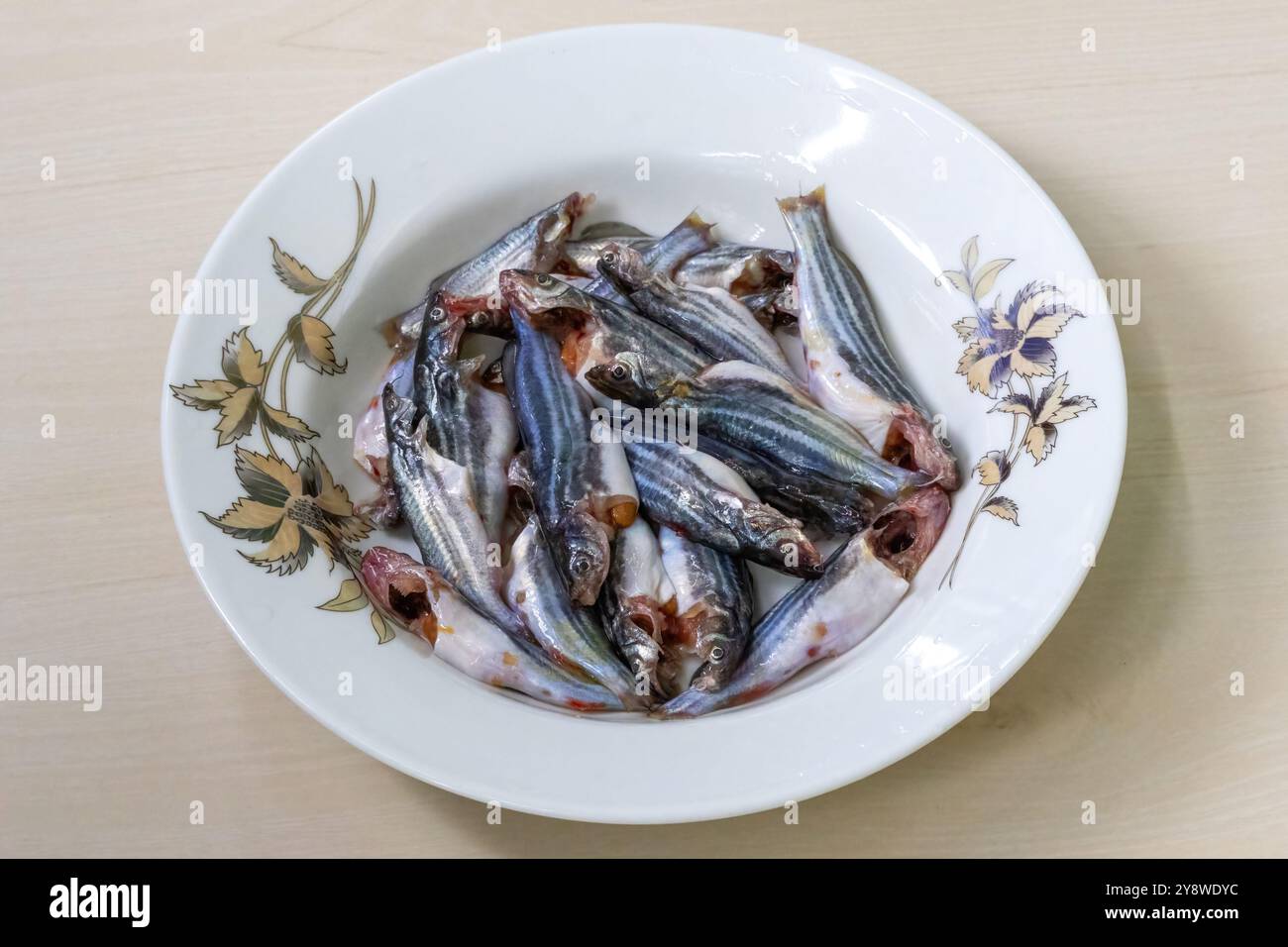 Uncooked tengra fish after cutting and washing on a plate. Ready to ...