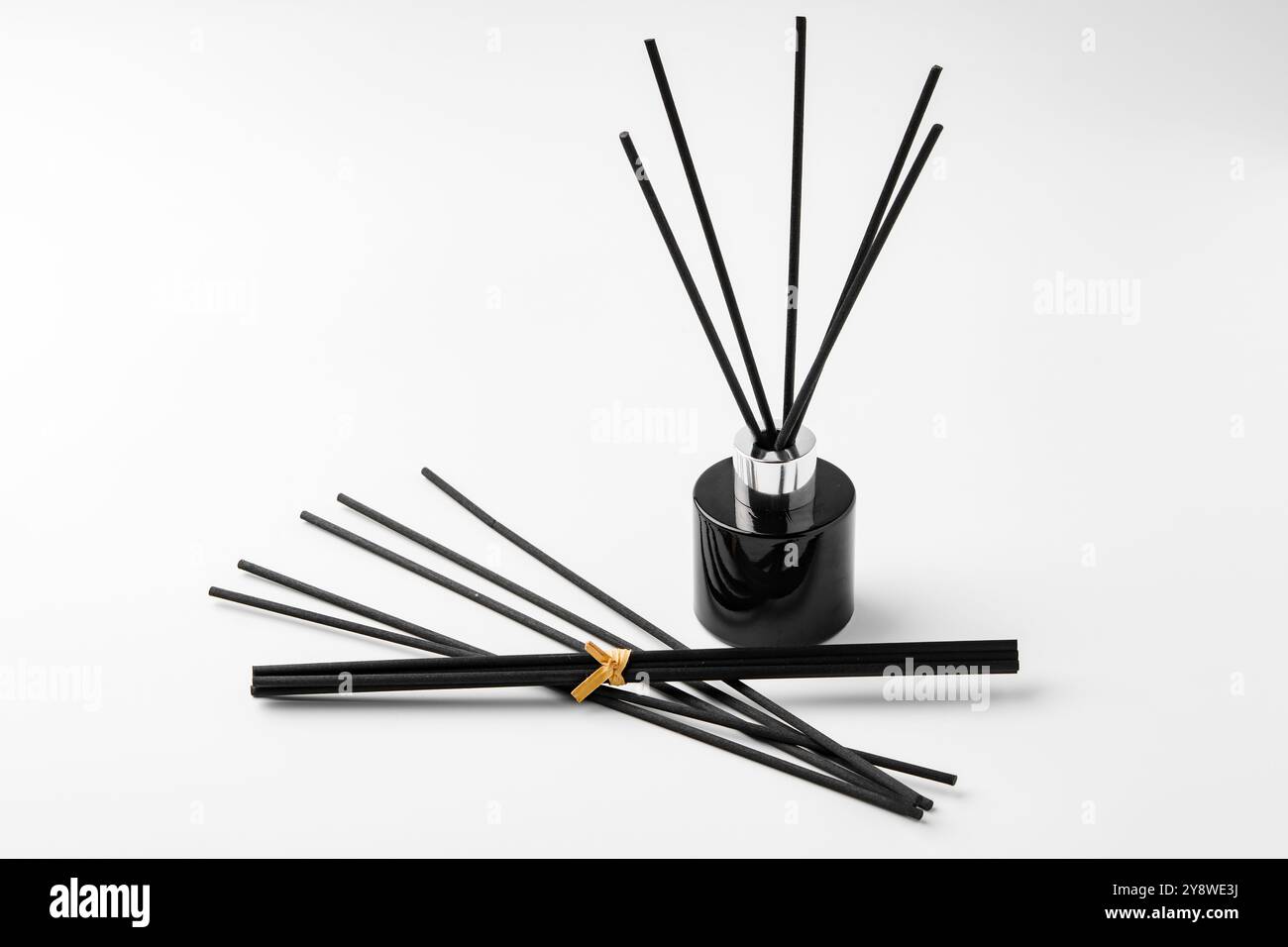 A minimalist display of essential oil and black diffuser sticks on a ...
