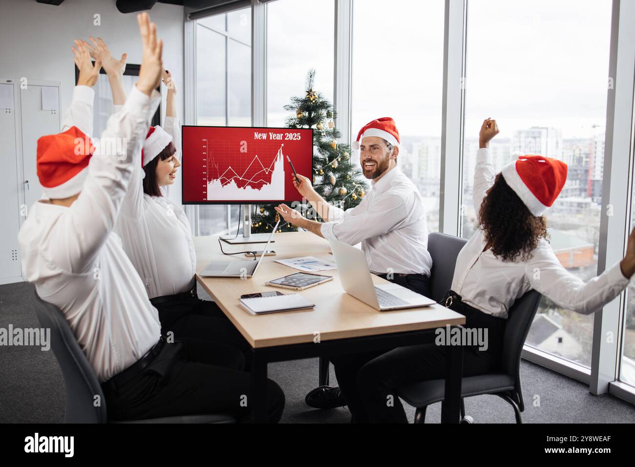 Successful team of multiethnic business people in Santa hats raising ...