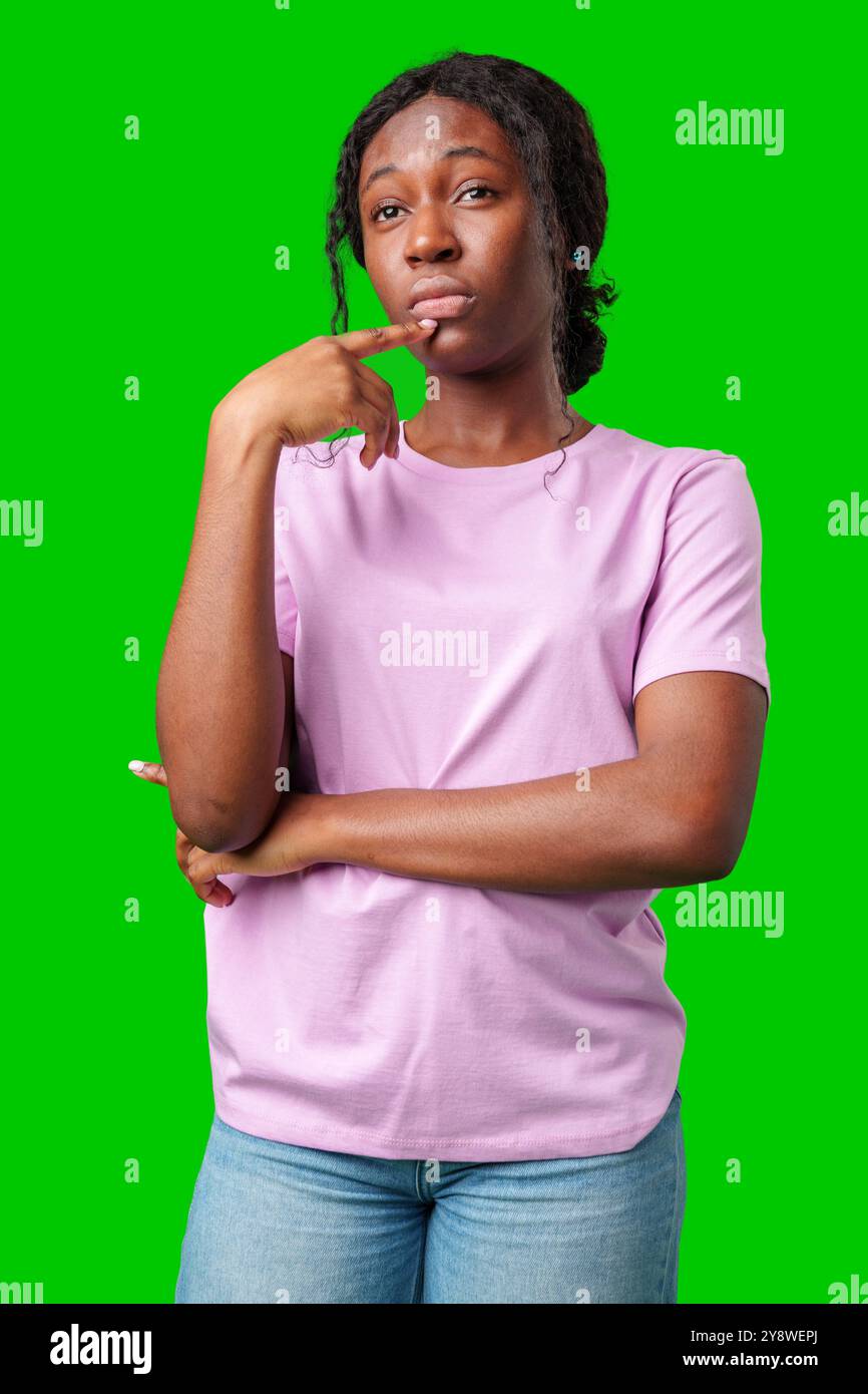 Thoughtful woman pondering in front of a bright green background during ...