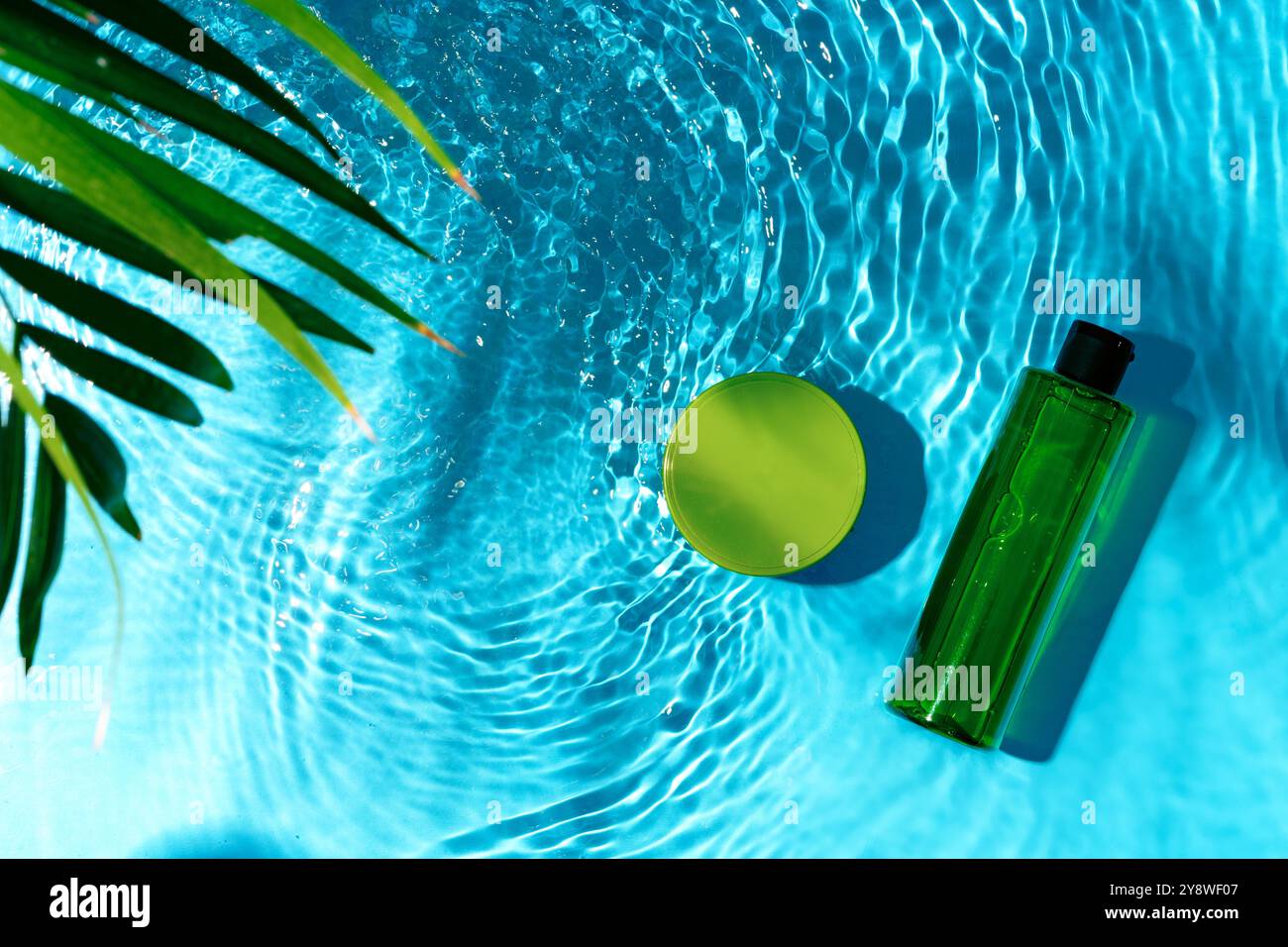 Green bottle floating on a clear blue swimming pool during bright ...