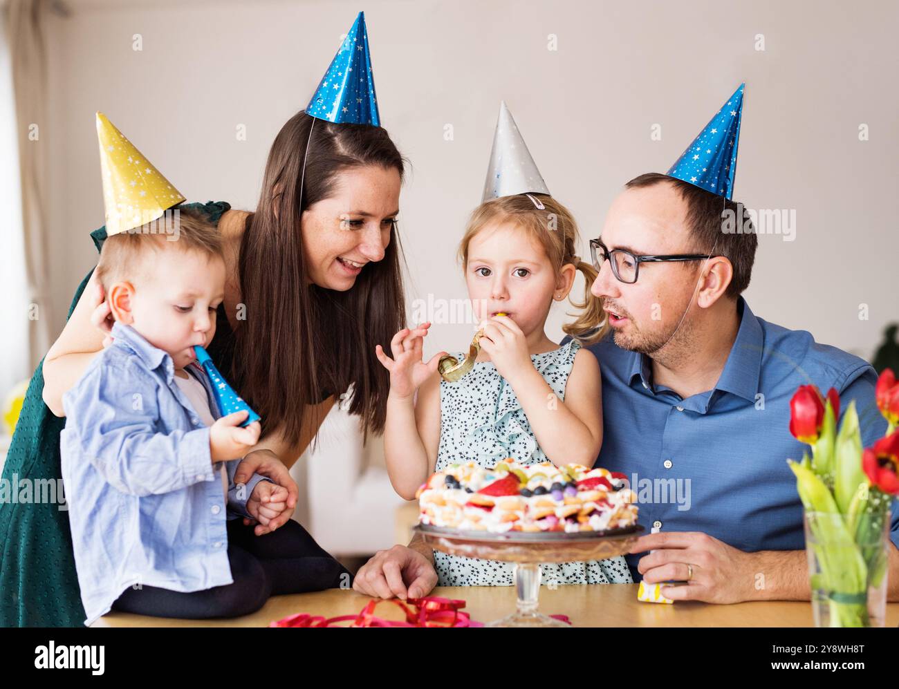 Birthday party with birthday cake. Parents and two kids having surprise ...