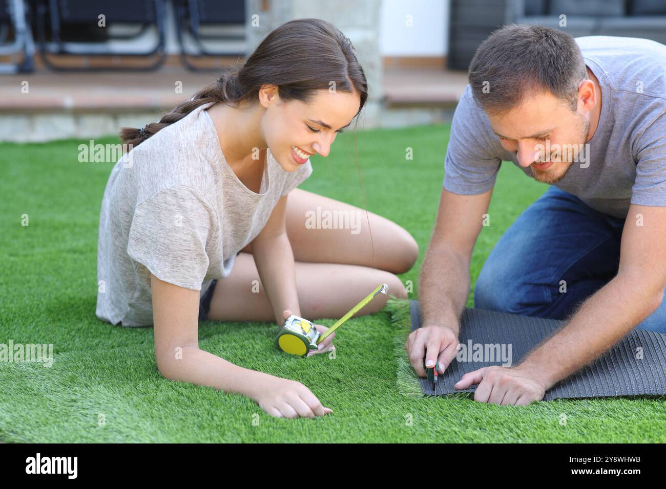 Happy couple installing artificial turf in the garden at home Stock ...
