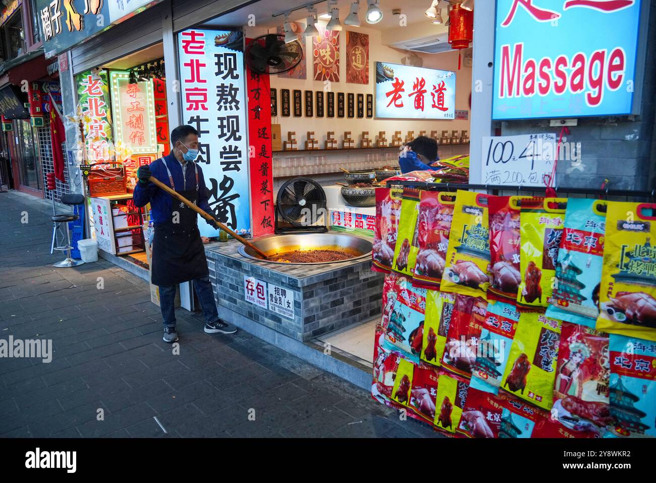 A man cooks in front of his a store in Beijing, China, Monday, Oct. 7 ...