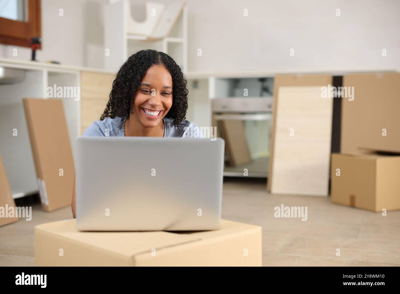 Black woman checking laptop in the kitchen moving home Stock Photo - Alamy