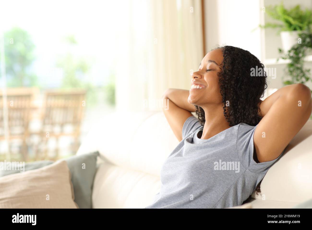 Happy black woman relaxing on a a sofa in the living room sitting at ...