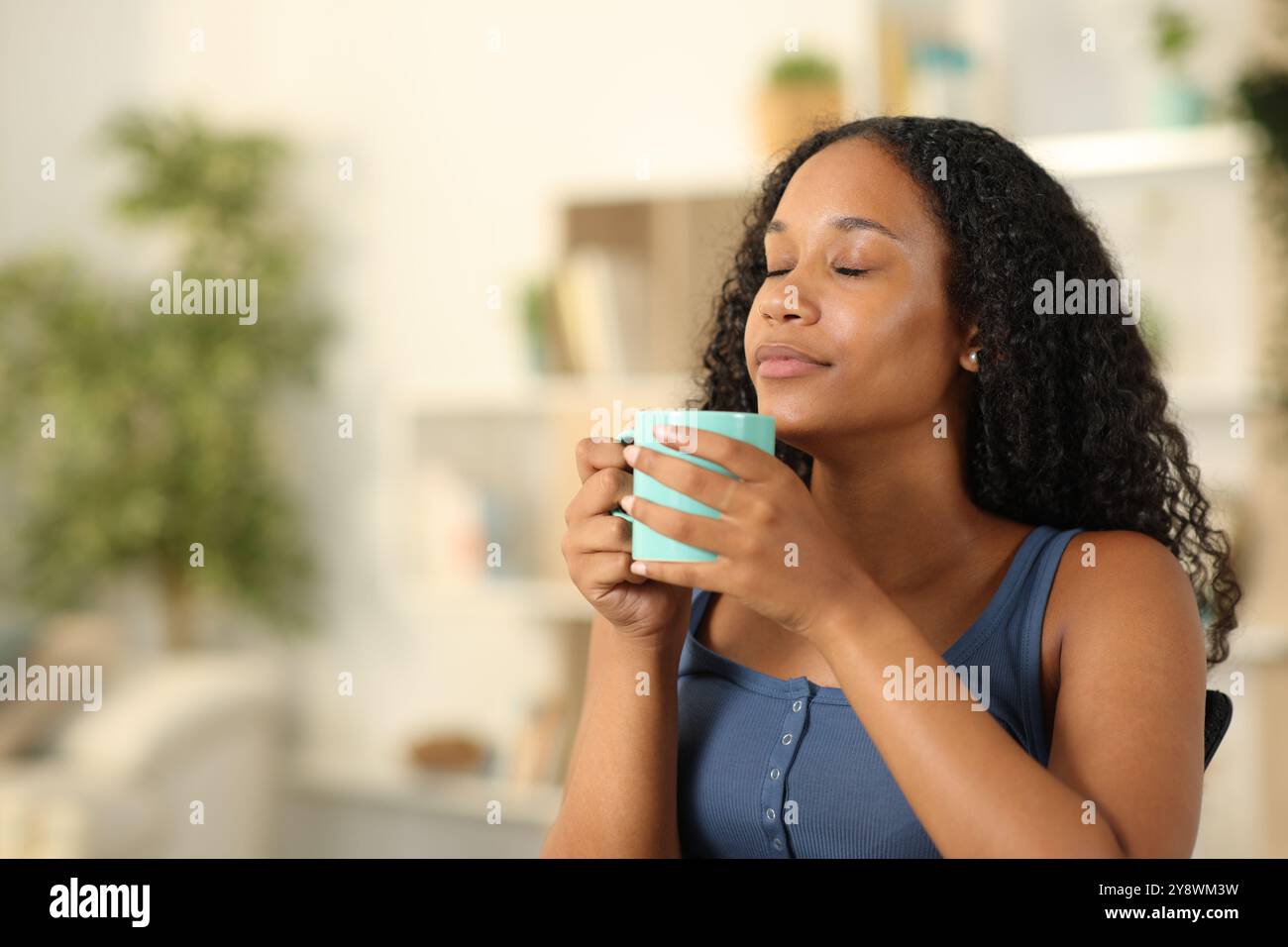 Portrait of a relaxed black woman smelling coffee or tea at home Stock ...
