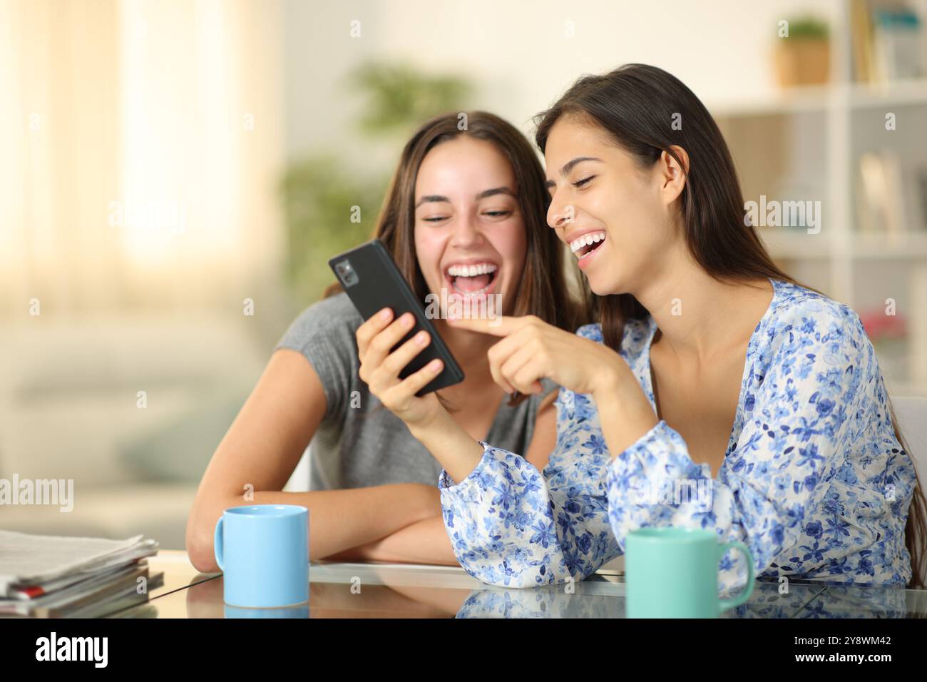 Two happy friends laughing checking smart phone hilarious content at ...