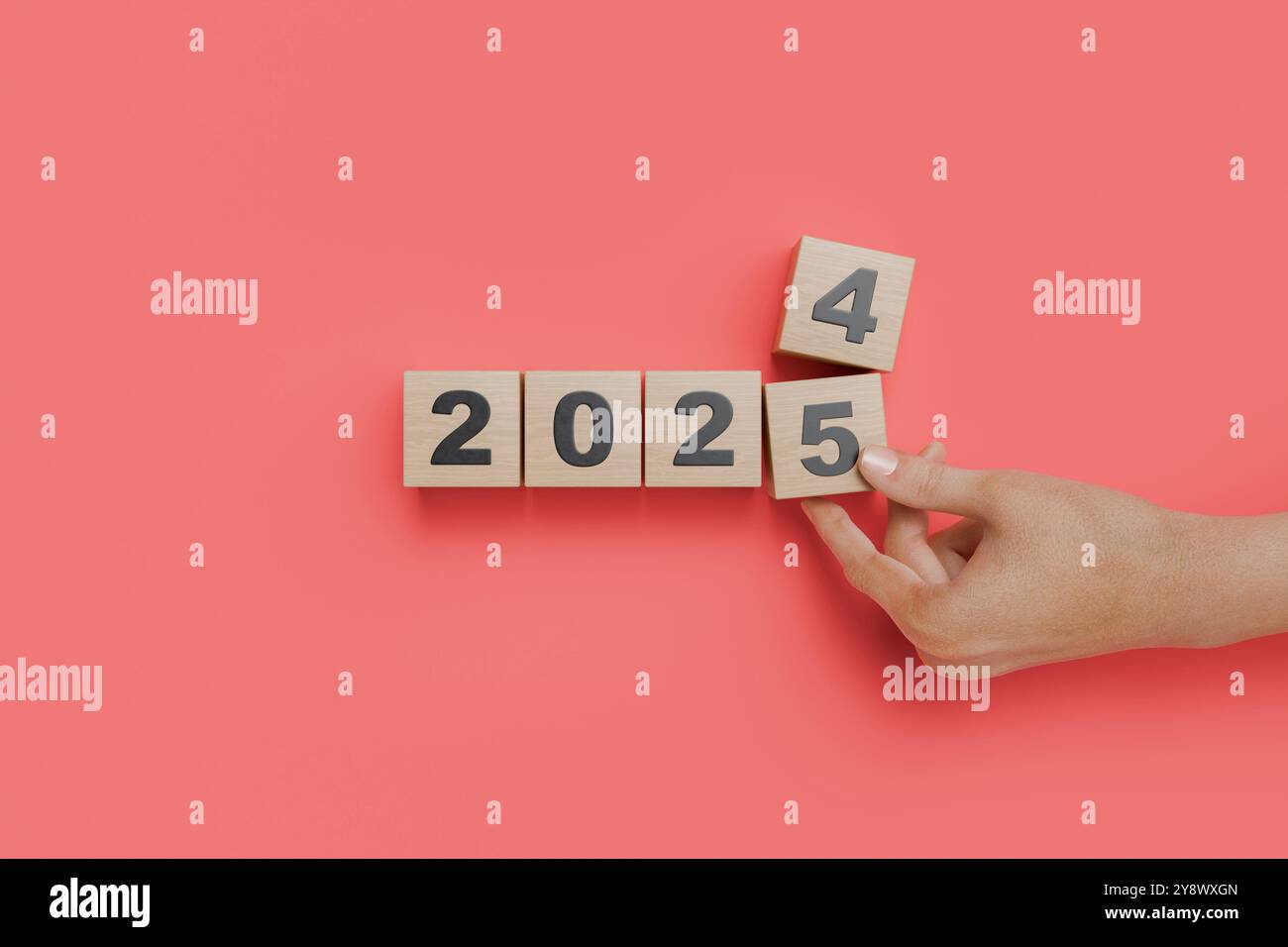 Hand changing wooden cubes from 2024 to 2025 on red background ...