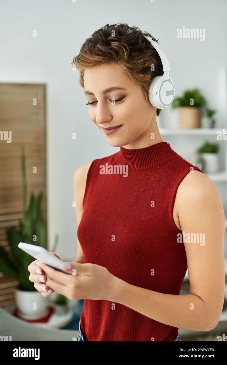 In a cozy home setting, a short-haired young woman enjoys music while ...