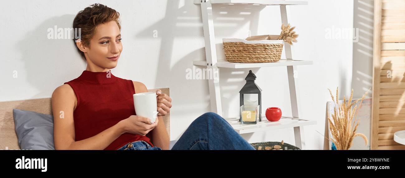 A young woman with short hair relaxes at home, sipping tea while ...