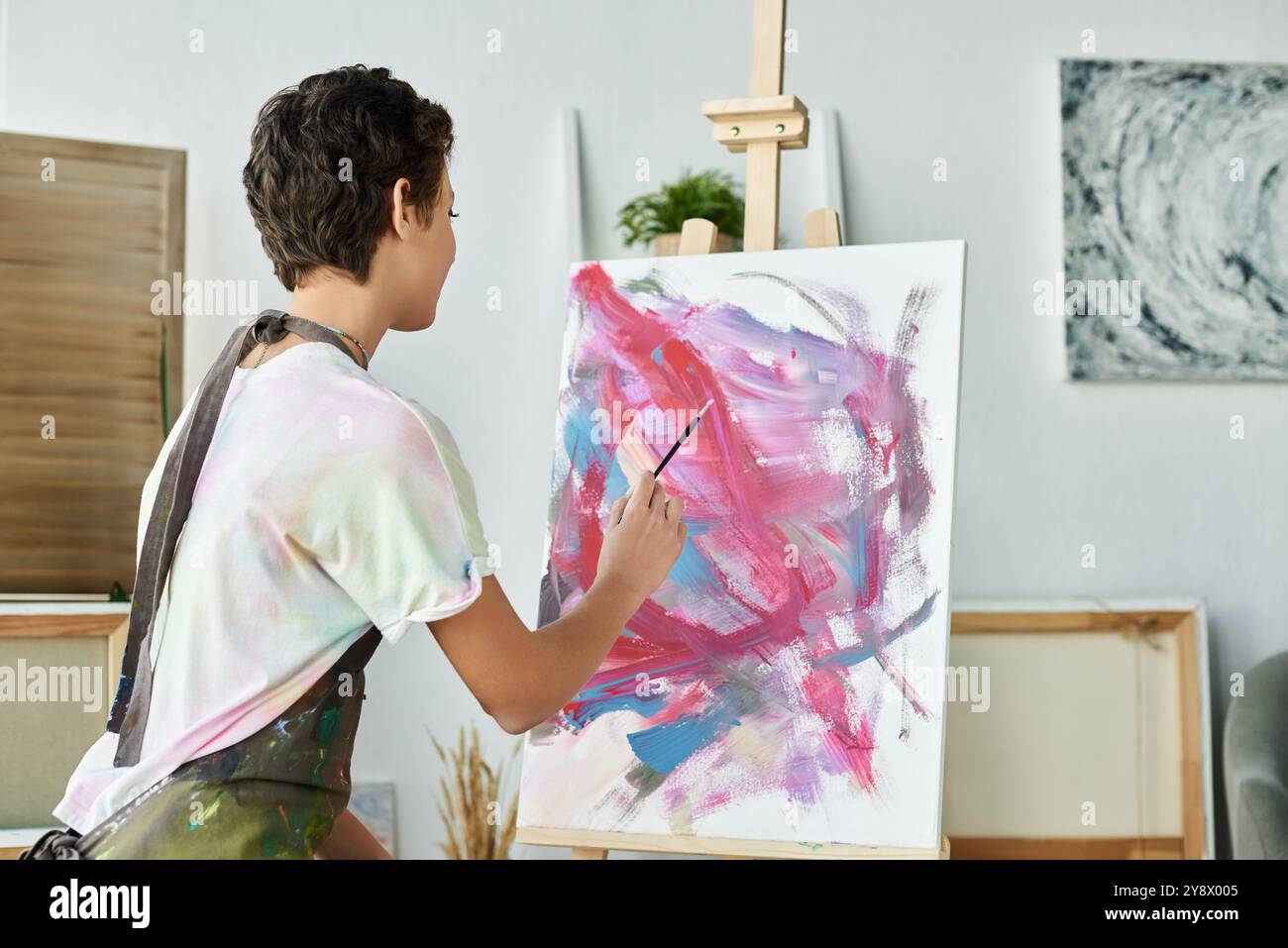 A young woman expresses her creativity by painting a vibrant picture at ...