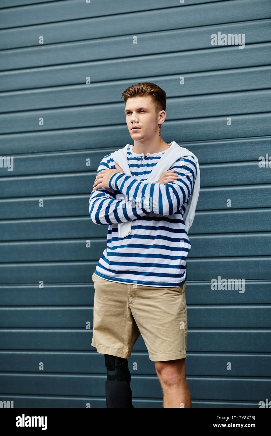 A young, handsome man stands with confidence, arms crossed, showcasing ...