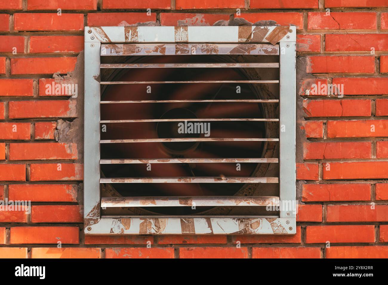 Industrial ventilation fan in operation on a pig farm with brick wall ...