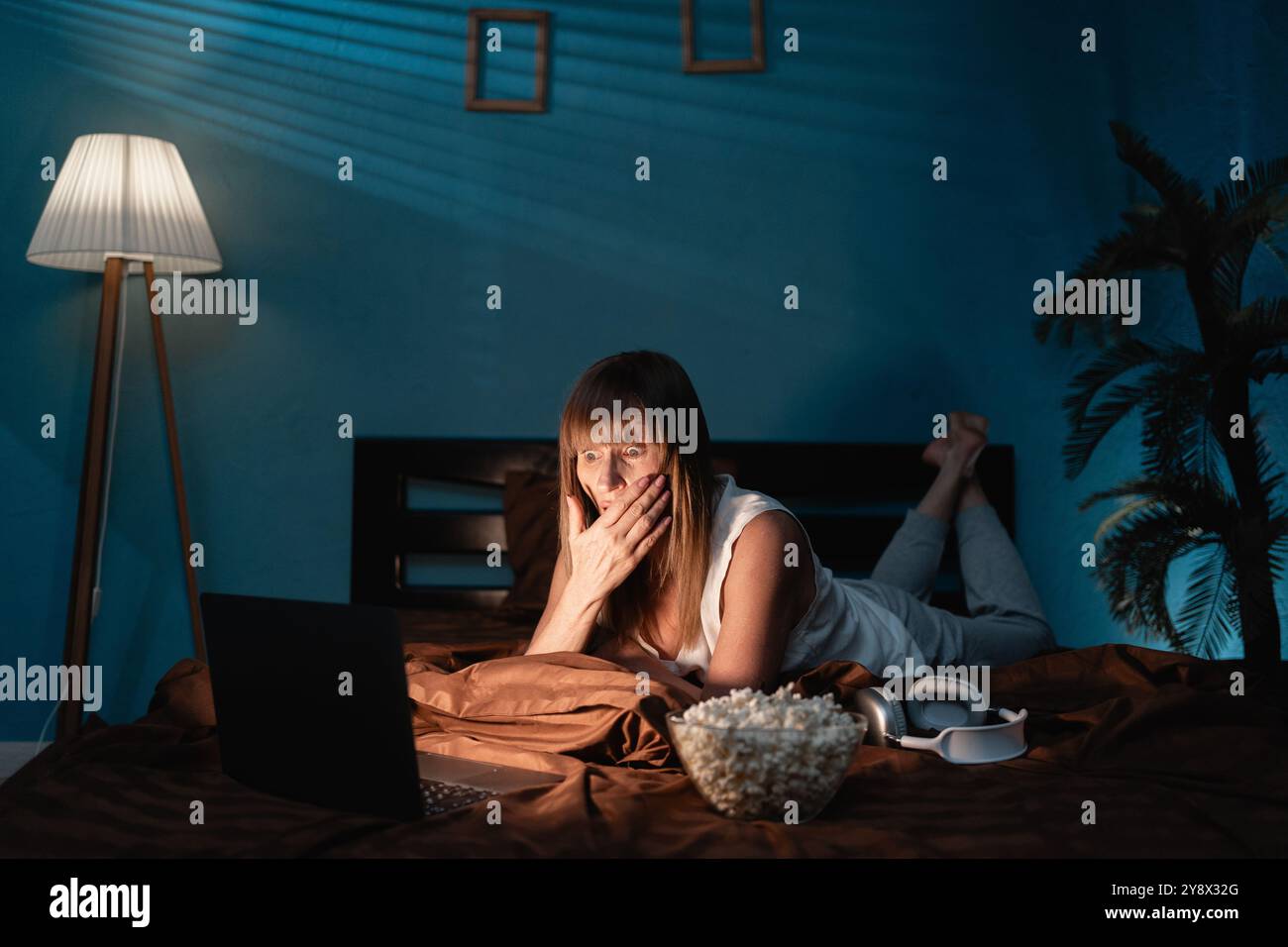 scared mature woman watching horror movie on bed. horror movie concept ...
