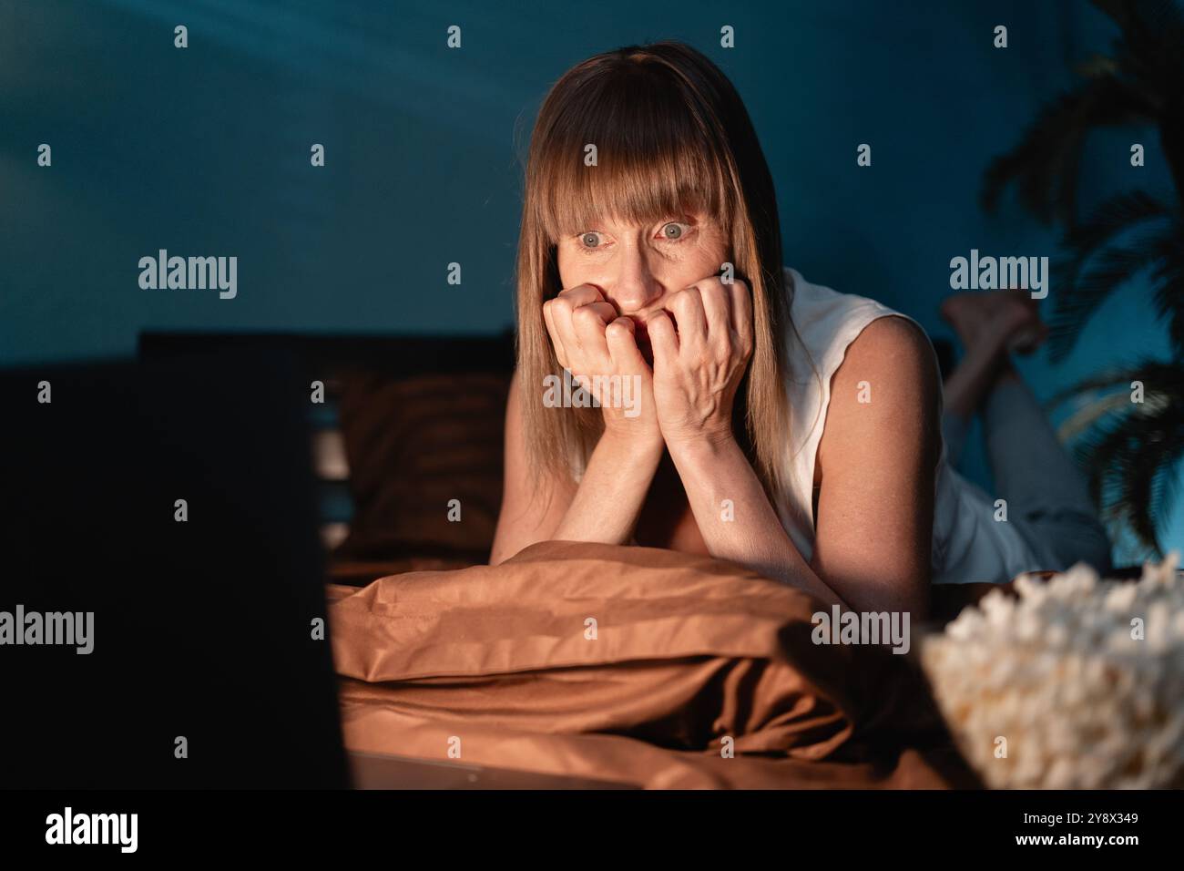 scared mature woman watching horror movie on bed. horror movie concept ...