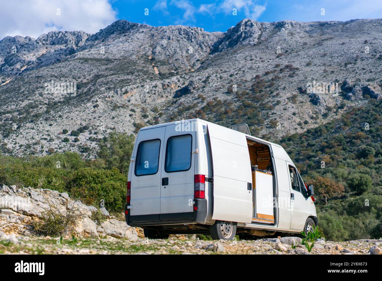 Brown dog looking out of a camper van window on a mountain landscape ...