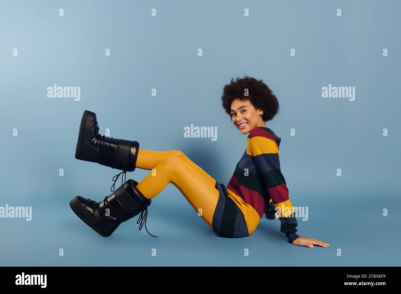 A young woman displays a cheerful expression, sitting on the floor in ...