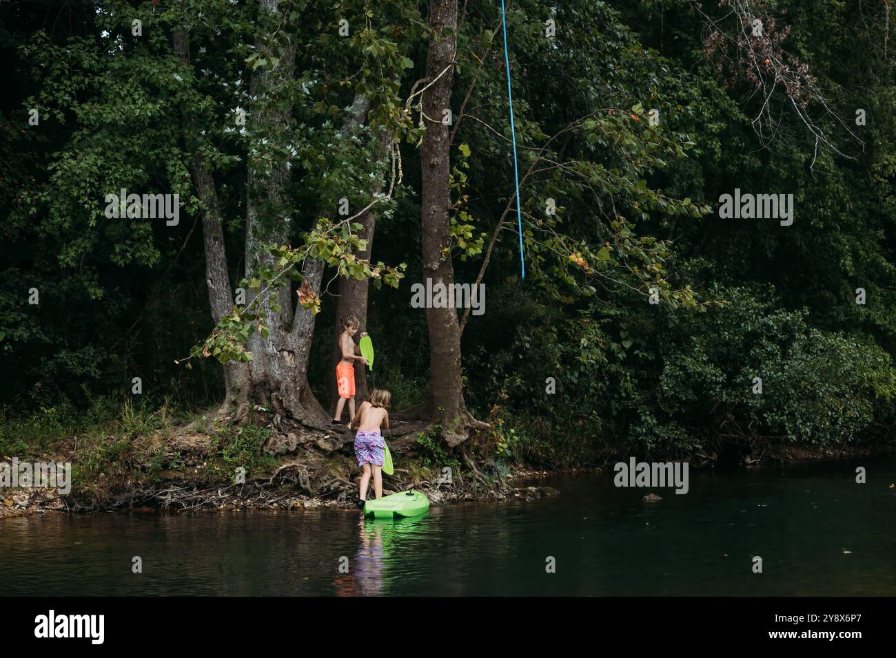 Adventurous boys on riverbank with kayak Stock Photo - Alamy