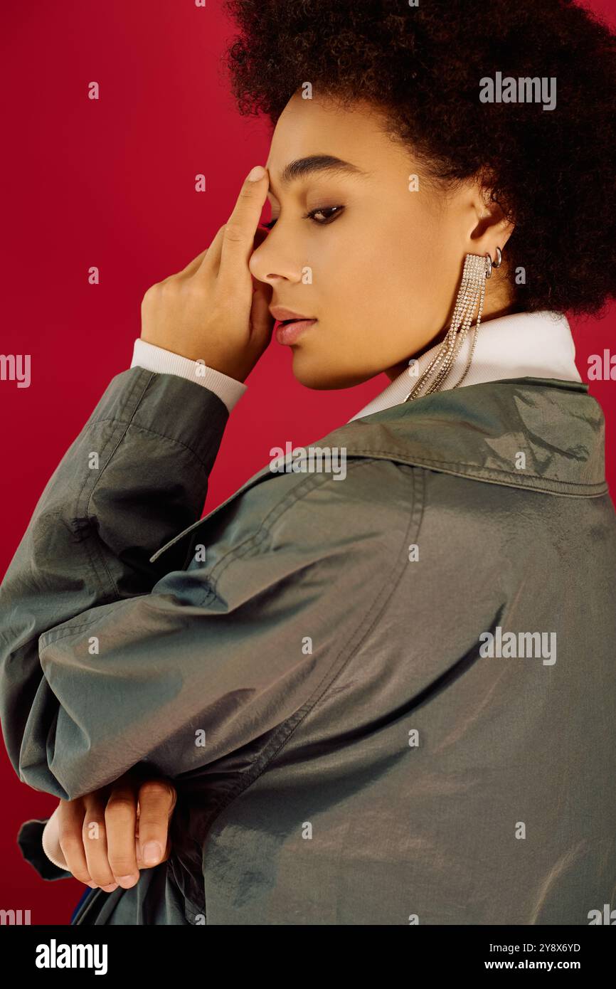 A young woman stands thoughtfully against a bold backdrop, expressing ...