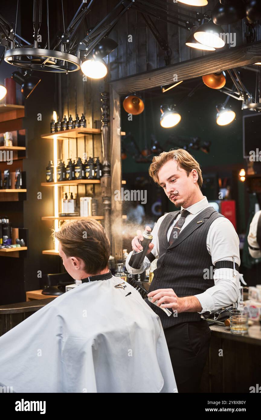 Professional barber using hairspray to finish hairstyle. Stylish ...