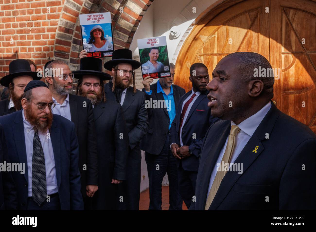 Members of the Jewish community listen and hold placards as Foreign ...