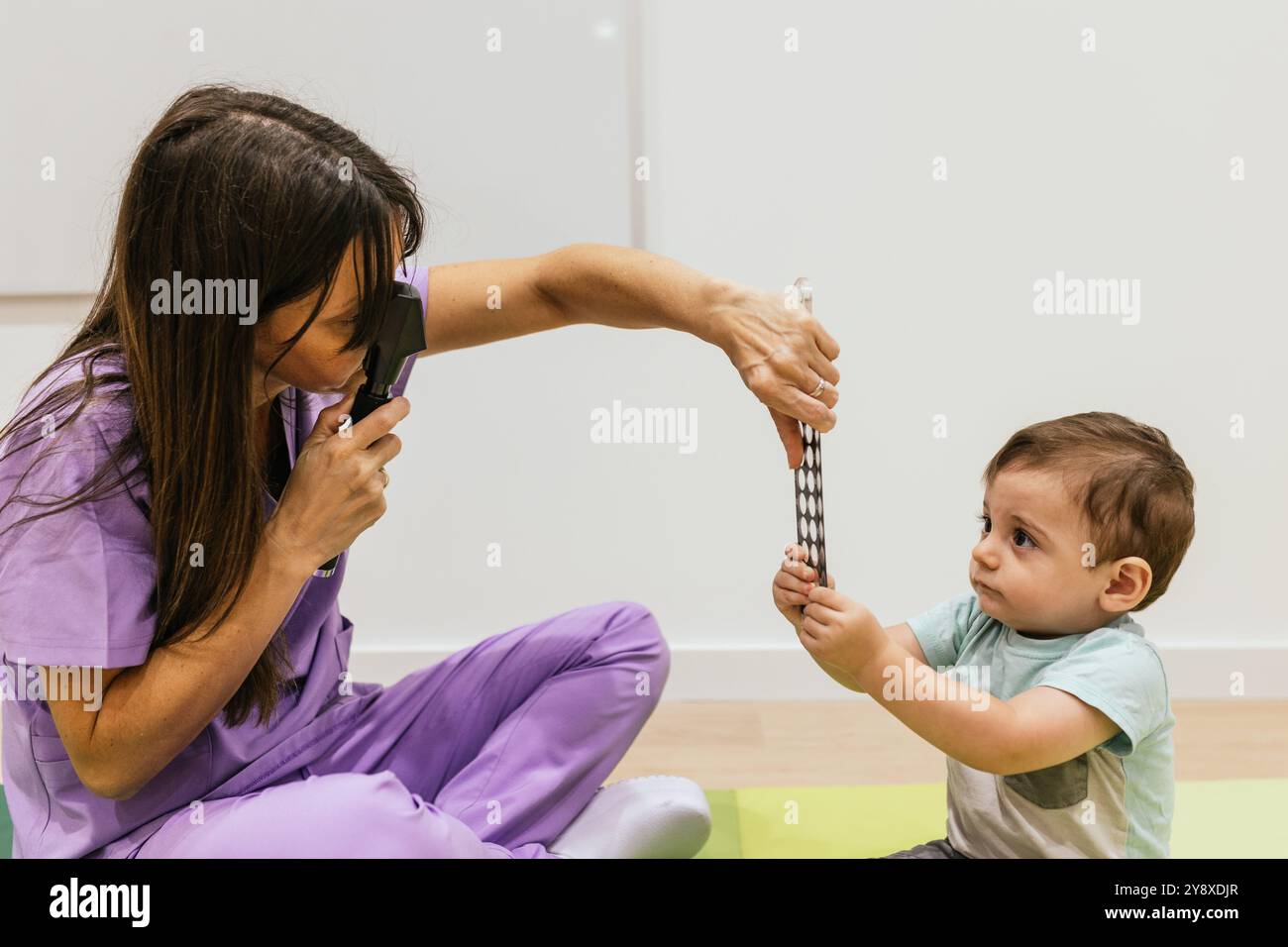 Female optometrist performing retinoscopy exam on toddler boy using ...