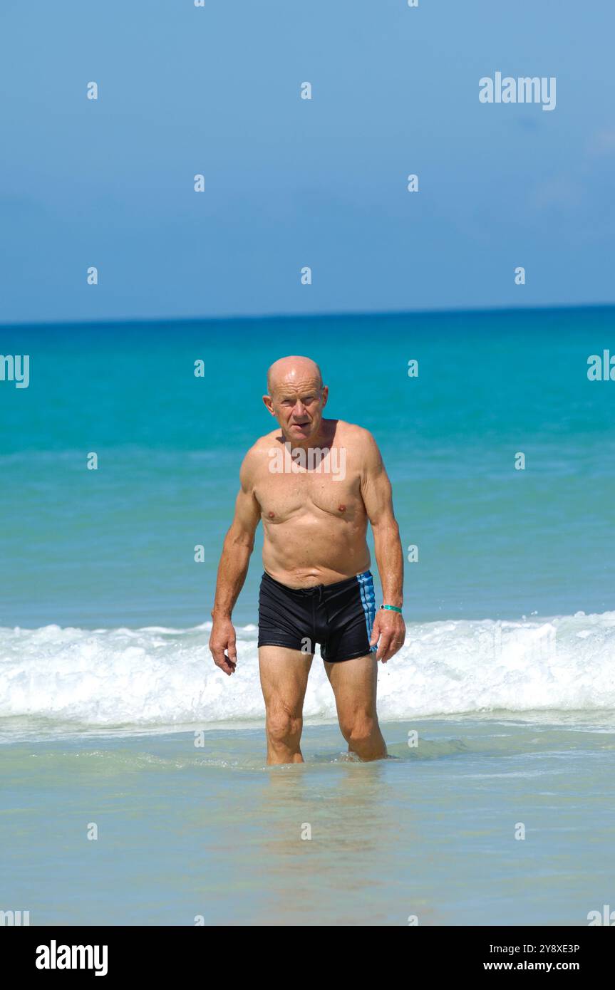 A senior man is standing in the water about to swim. Beach at Varadero ...