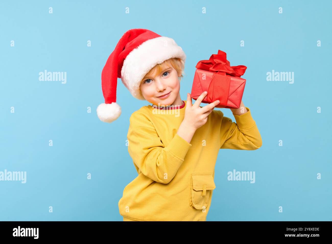Cute boy wearing red santa hat holding wrapped christmas present ...