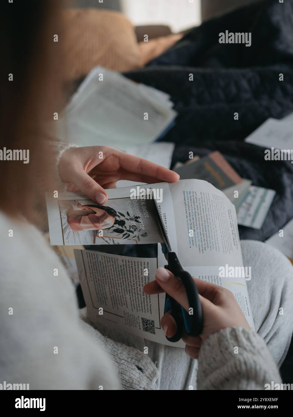 Woman scrapbooking cutting magazines for a vision board with scissors ...