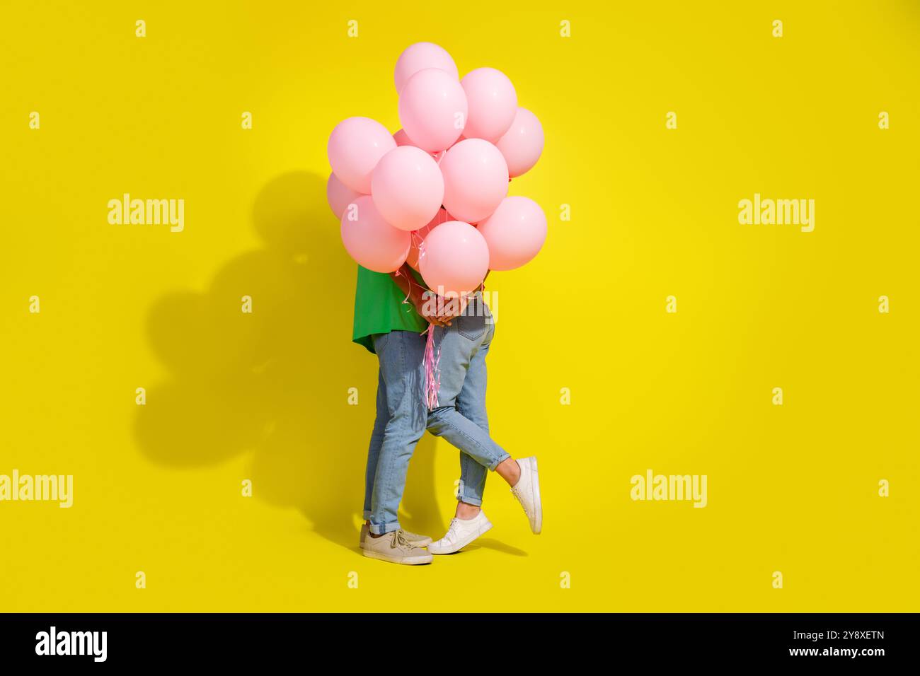 Full size photo of two nice young people hide behind balloons kiss ...