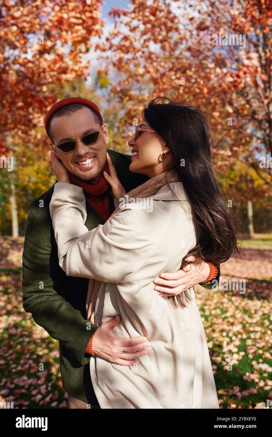 A couple shares a loving moment while surrounded by vibrant autumn ...