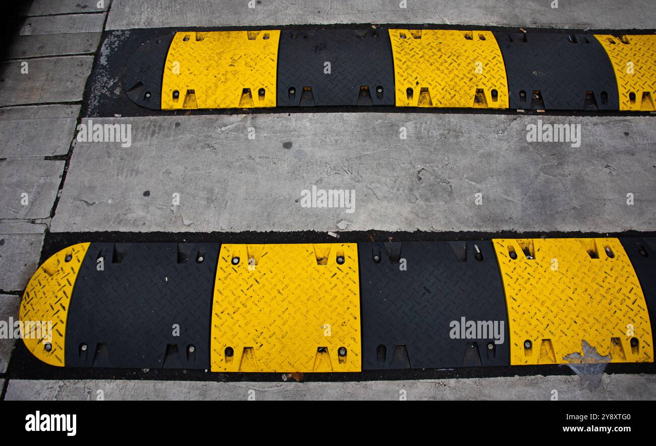 Yellow and black speed bumps contrast with the siding Stock Photo - Alamy