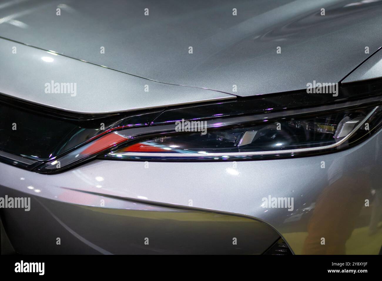 The image features a detailed closeup view of the headlight of a sleek ...