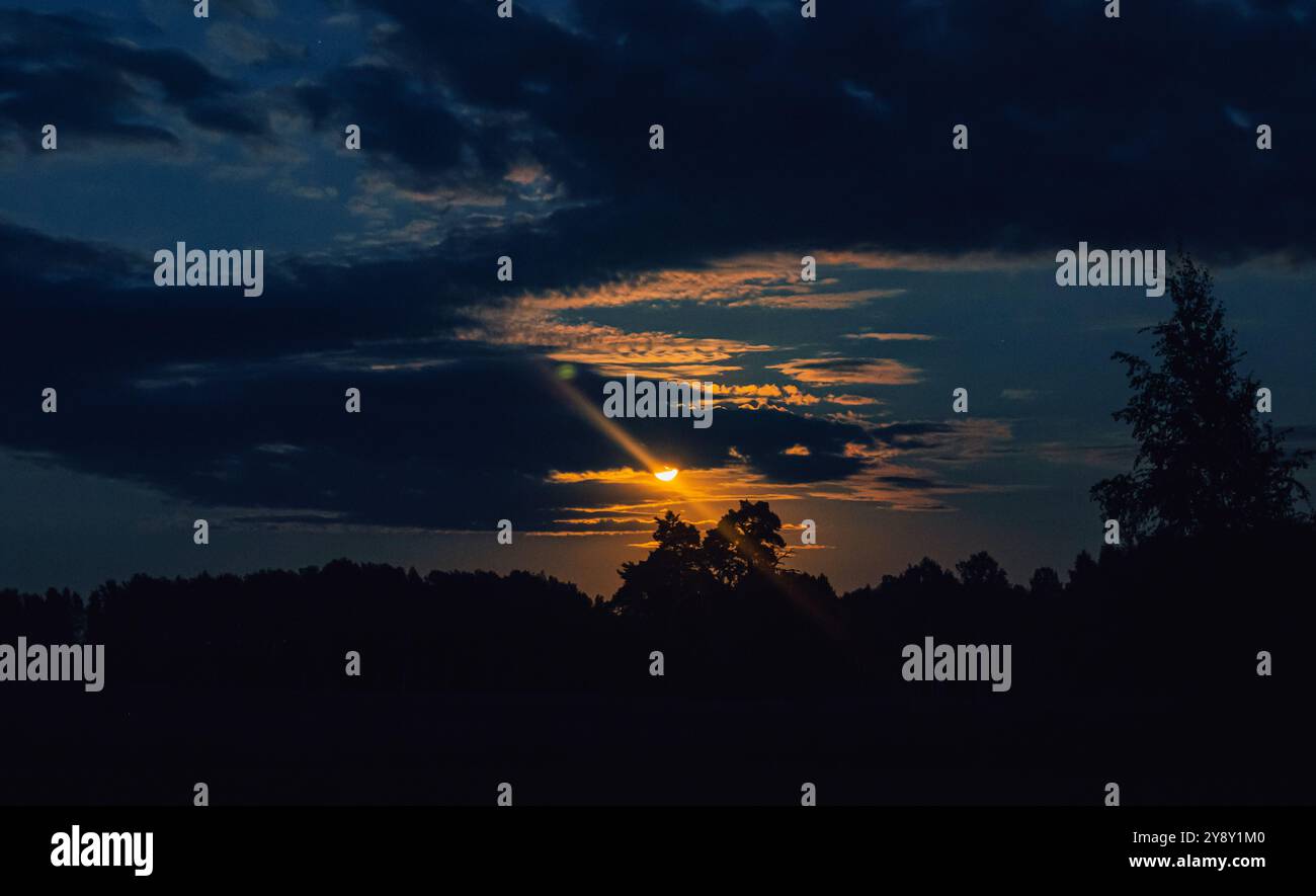 Night sky with a large round moon hiding behind clouds.Bright full moon ...
