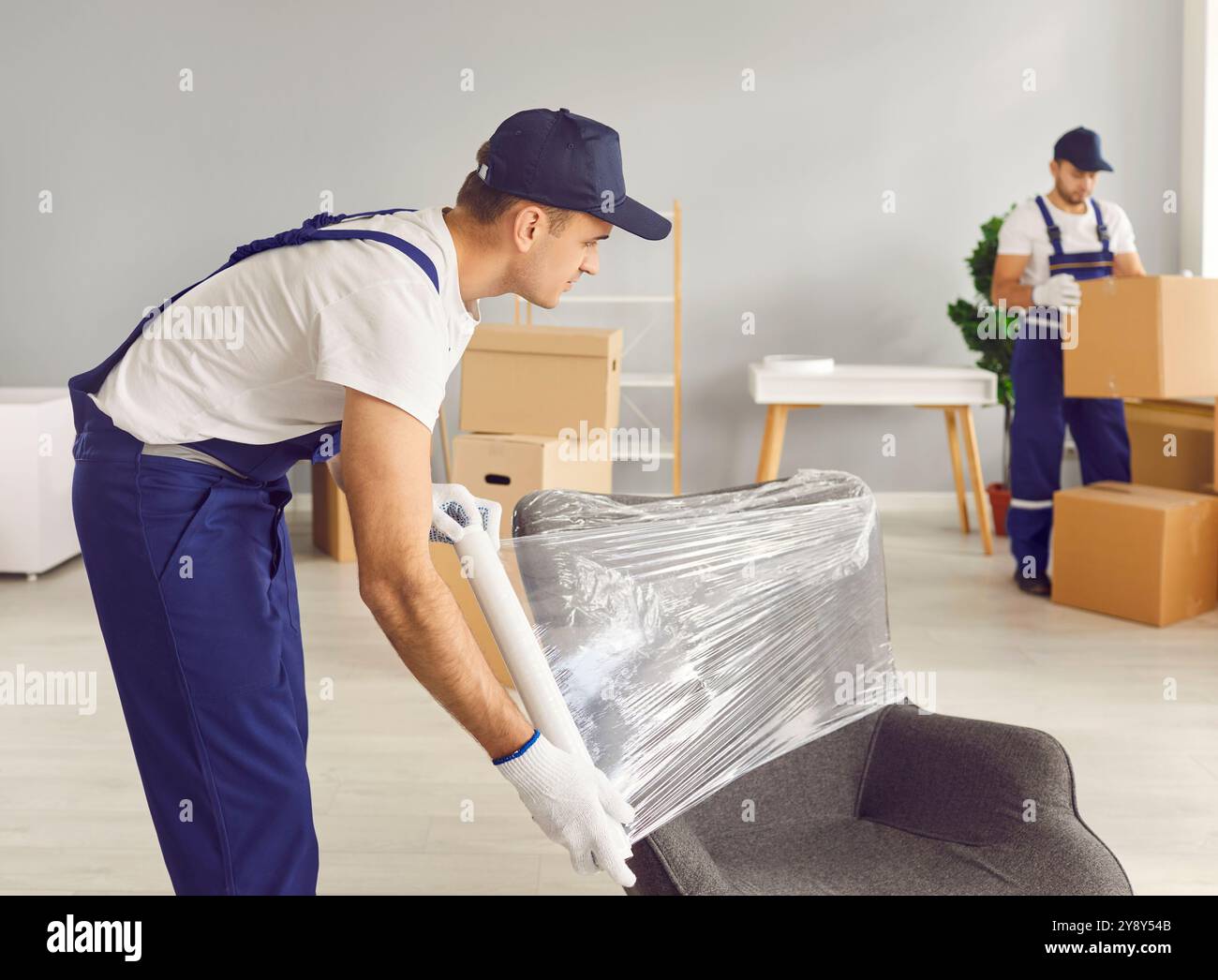 Loader wraps chair with transparent stretch film while completing order at moving service Stock ...