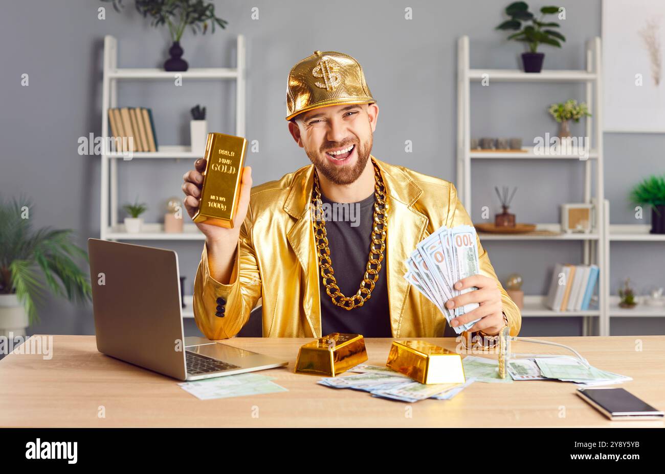 Happy rich guy with money working online, golden bullion, wearing gold ...
