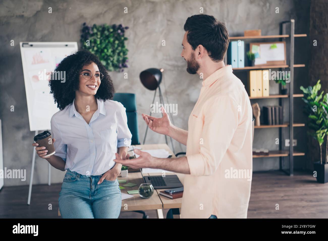 Photo of two young colleagues drink coffee chatting loft interior ...