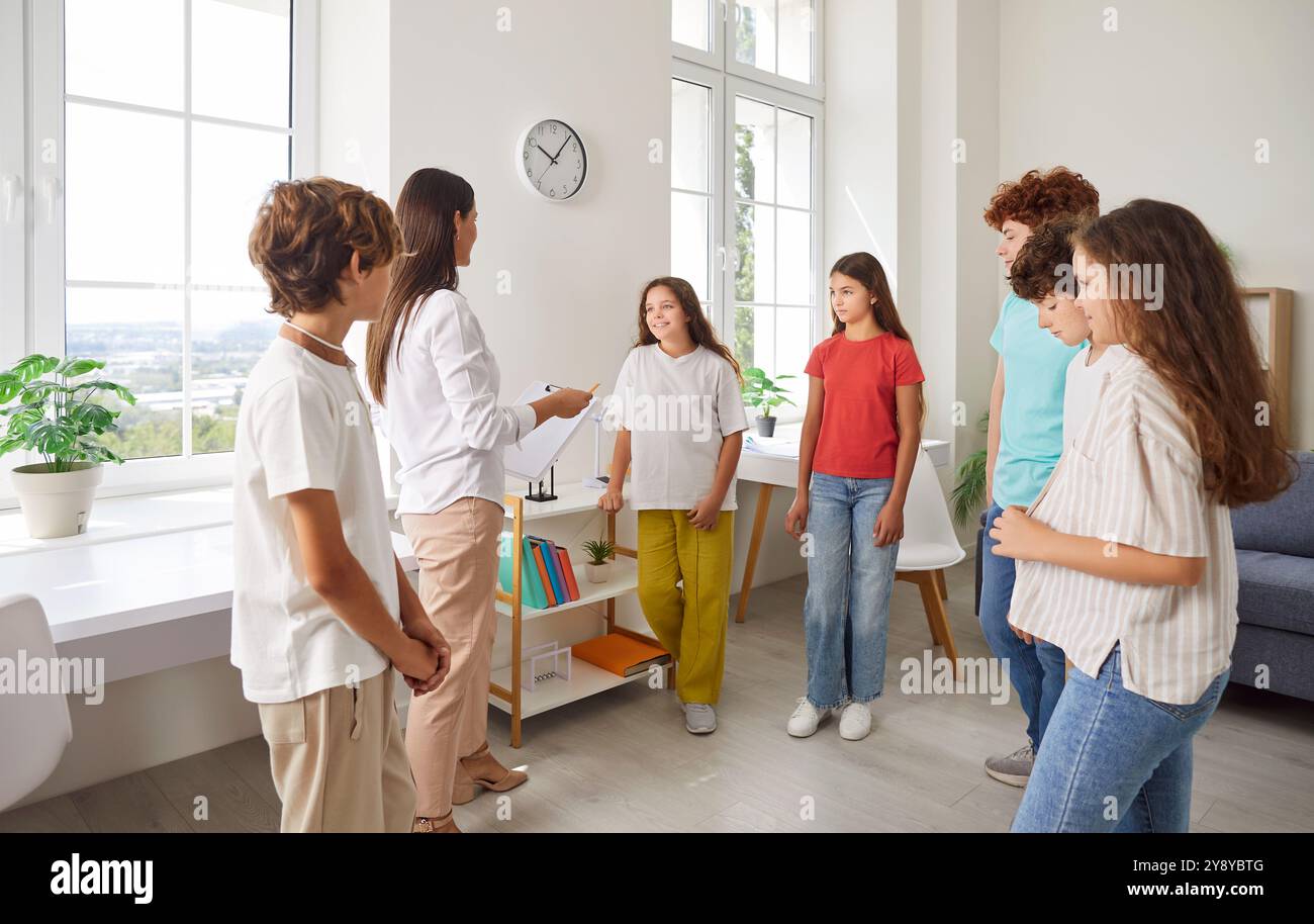 Group of school children talking with their teacher in classroom ...