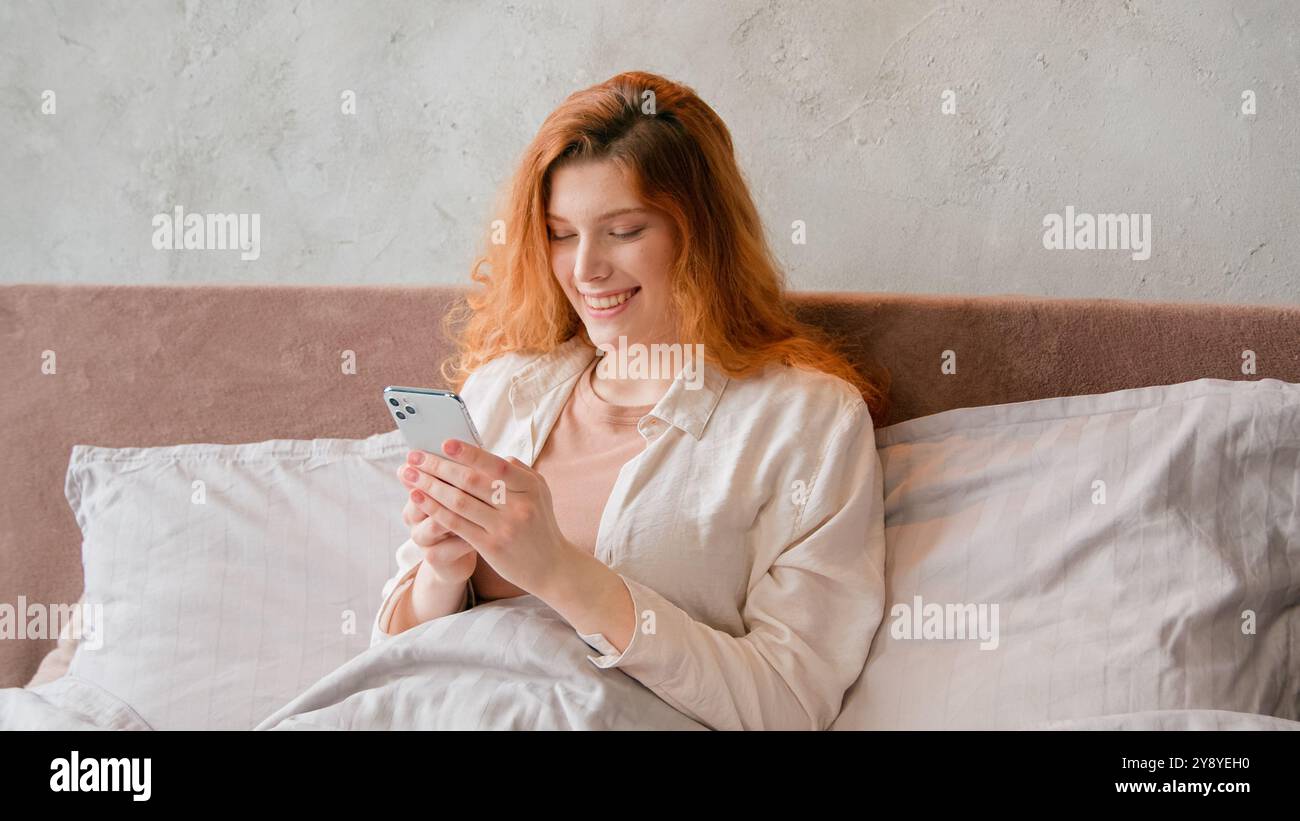 Relaxed Caucasian girl woman in bed at tranquil morning routine after wake up sleeping gadget ...